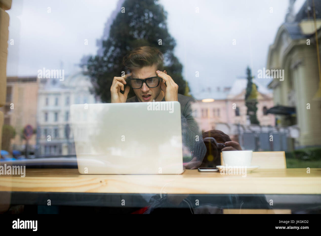 young man with head pain work at laptop view from window Stock Photo ...