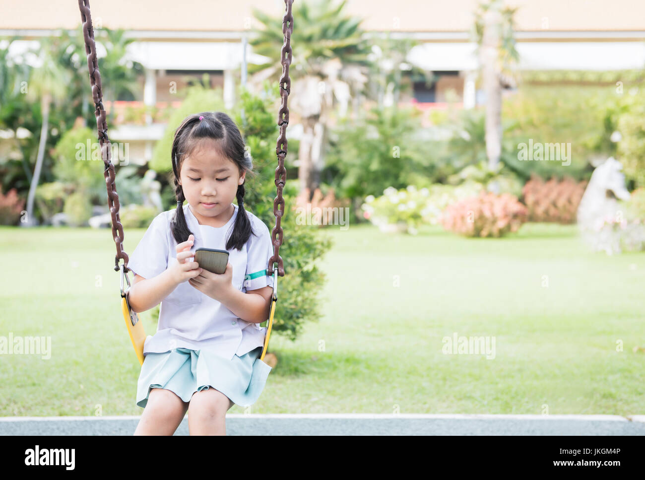 cute girl student play smart phone on swing in school playground Stock ...