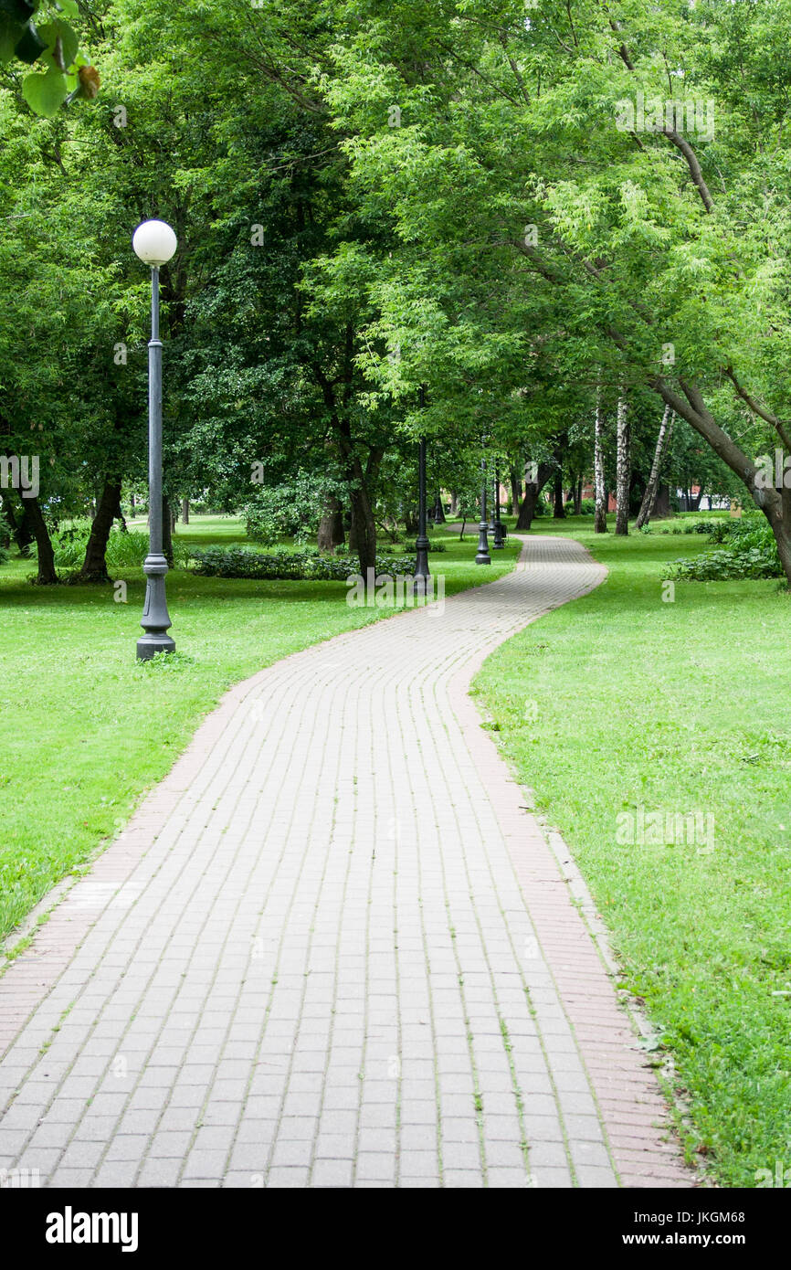 Road through the park with green grass and street lantern. background ...