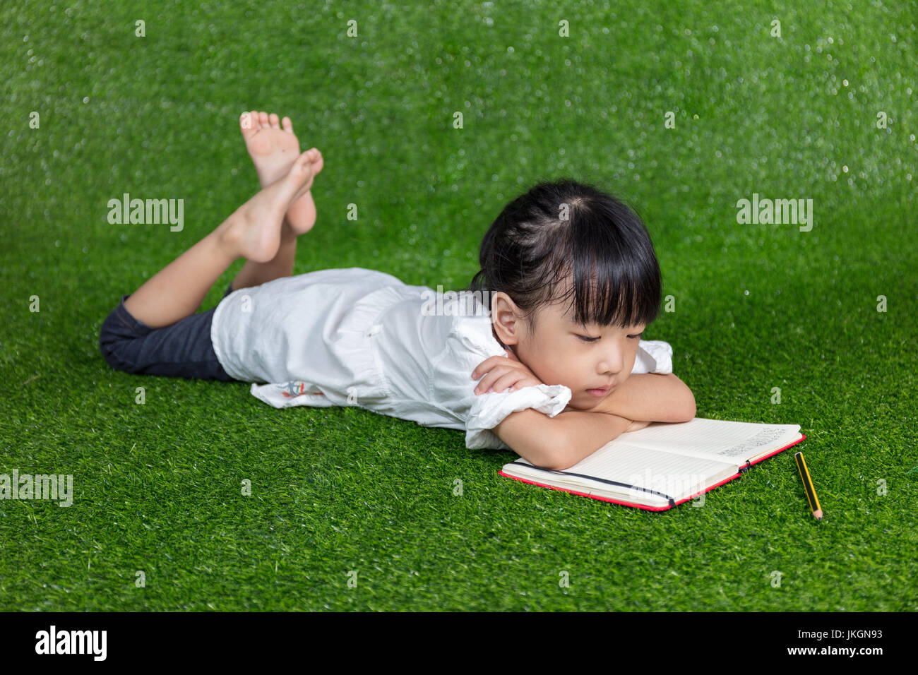 Asian Chinese little girl reading a book on green grass Stock Photo - Alamy