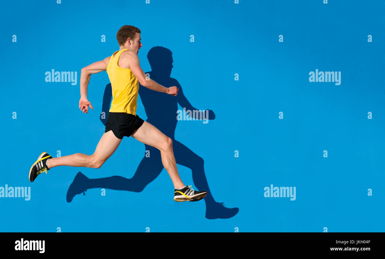 Long distance runner running past blue painted wall Stock Photo - Alamy