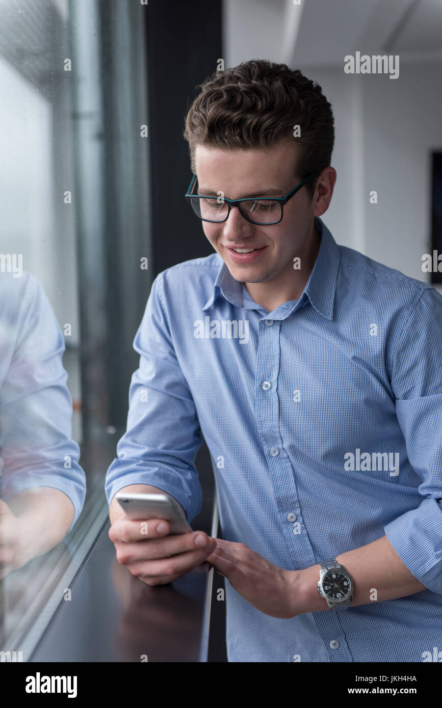 businessman using a phone beside window of modern office Stock Photo ...