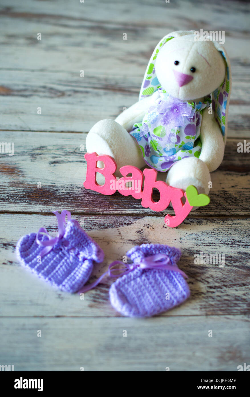 Purple knitted baby socks with an inscription of a child and a toy hare ...