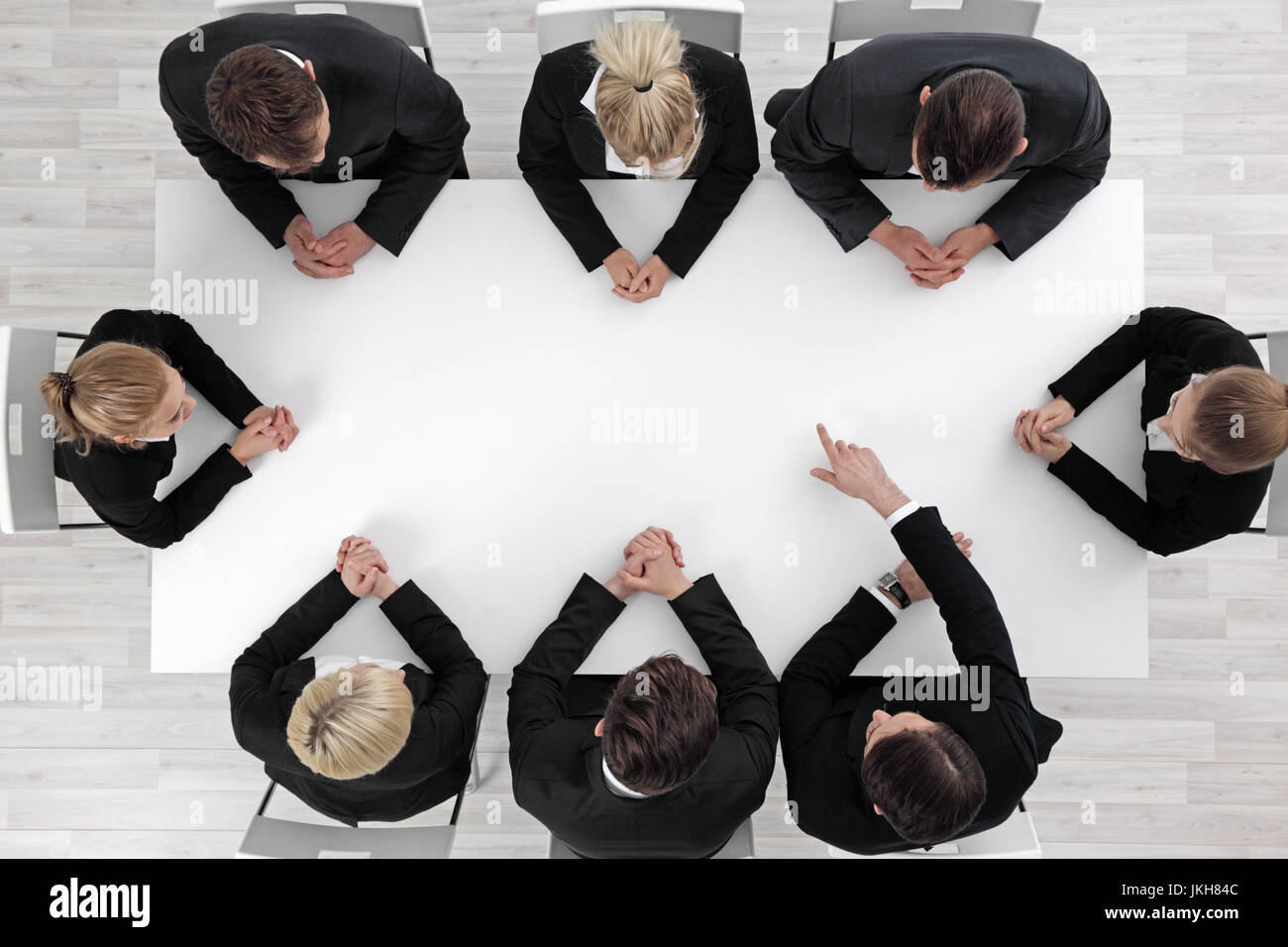 Business people sitting around empty table, business man pointing to ...
