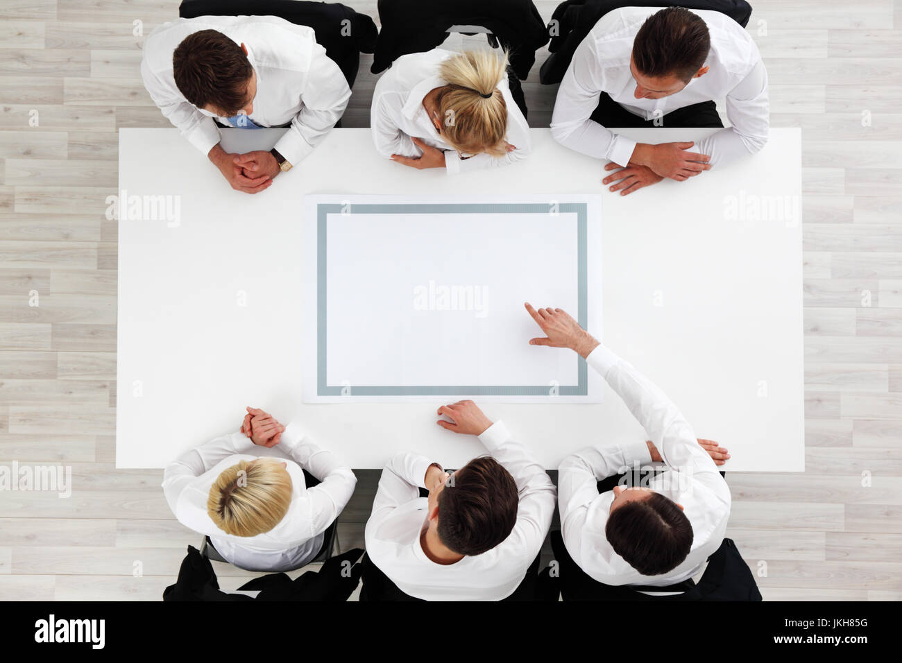 Business people sitting around empty table, business man pointing to ...