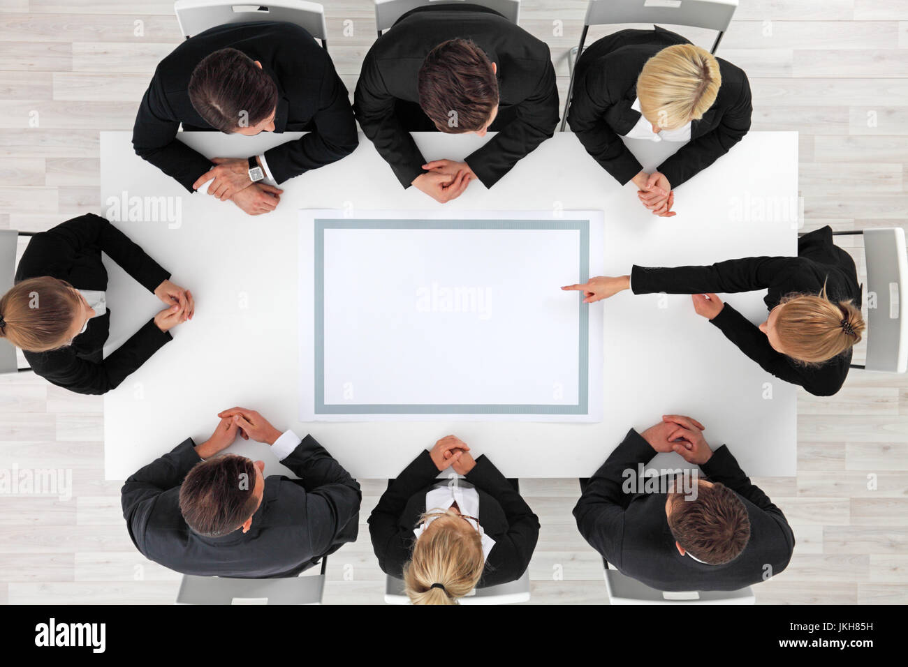 Business people sitting around empty table, business woman pointing to ...