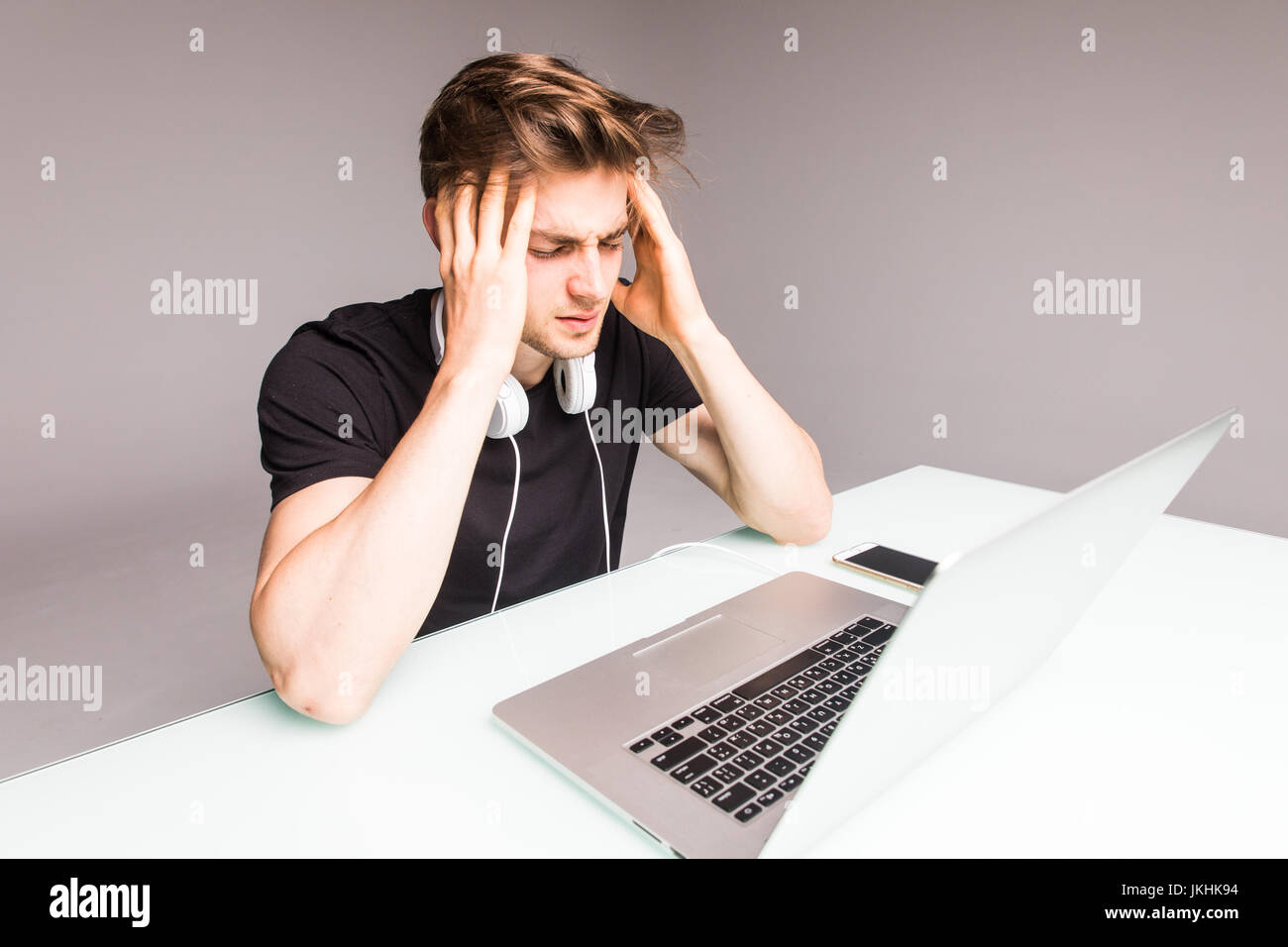 Handsome young man suffering from headache while working with laptop on ...