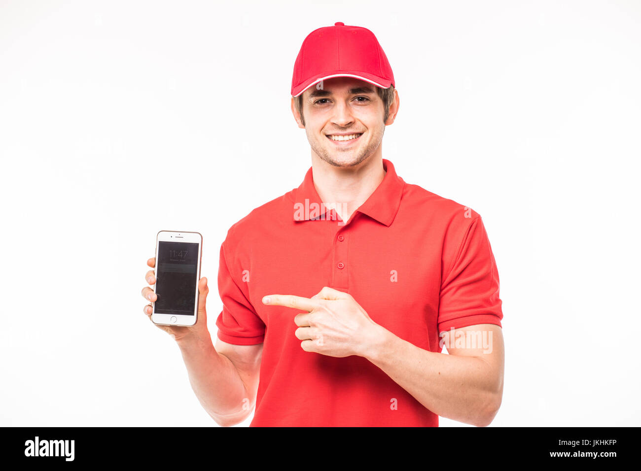 Happy courier with phone looking at camera isolated gray background ...