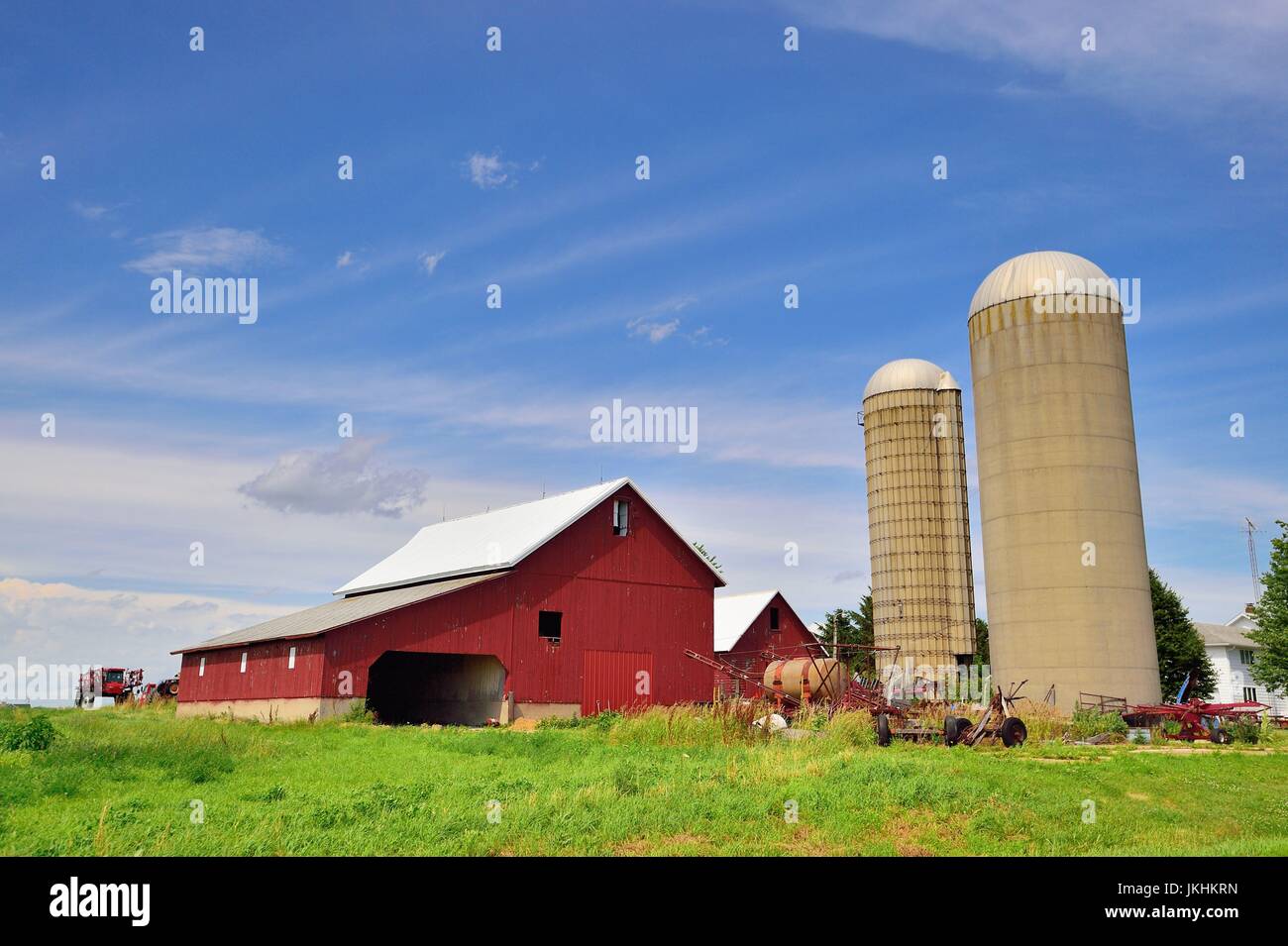 A red barn and silos sit among clutter and assorted buildings on a farm ...