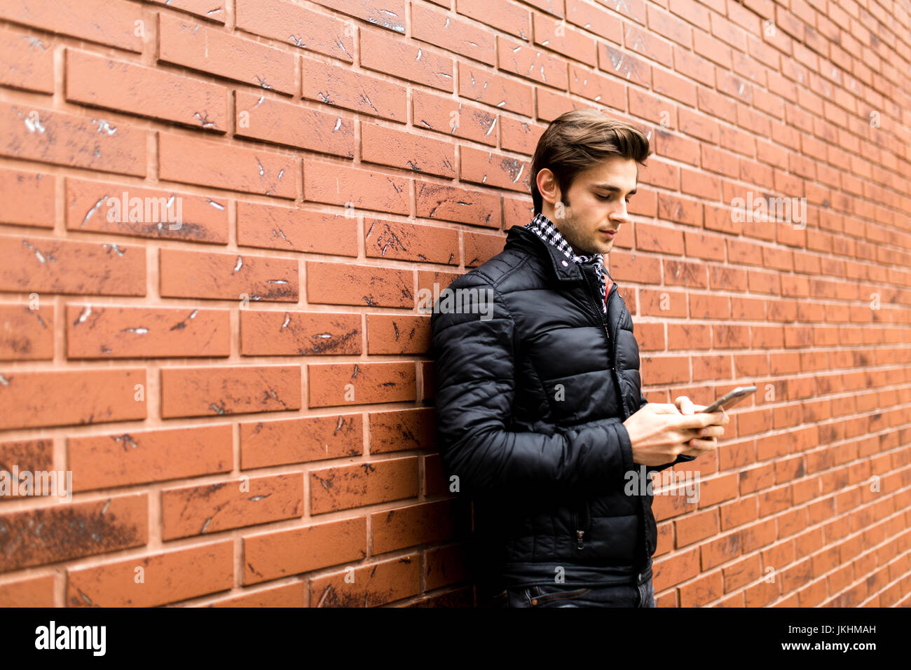 Handsome young man holding mobile phone and looking at it while ...