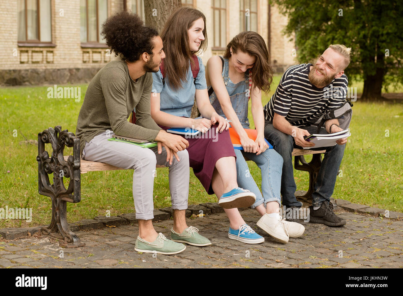 College friends sitting on bench in campus Stock Photo - Alamy
