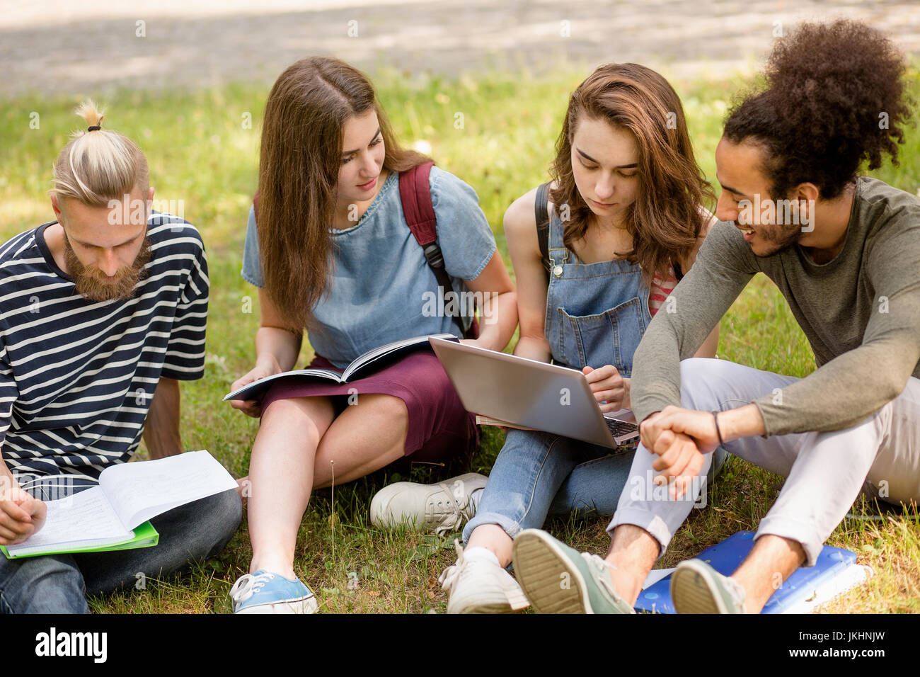 Group of students doing teamwork while sitting on lawn Stock Photo - Alamy