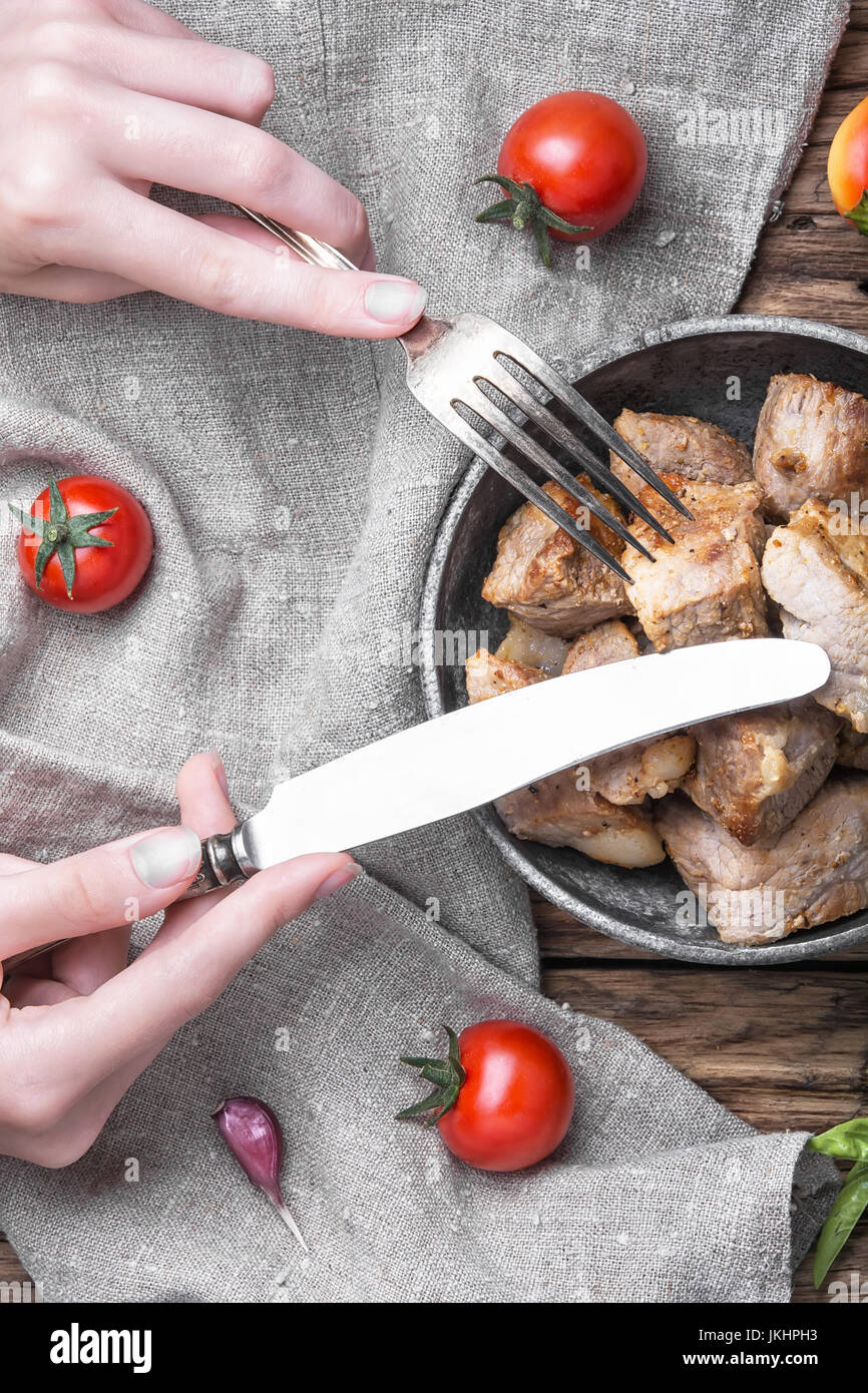 Hands with fork and knife, cutting pork meat for dinner Stock Photo - Alamy