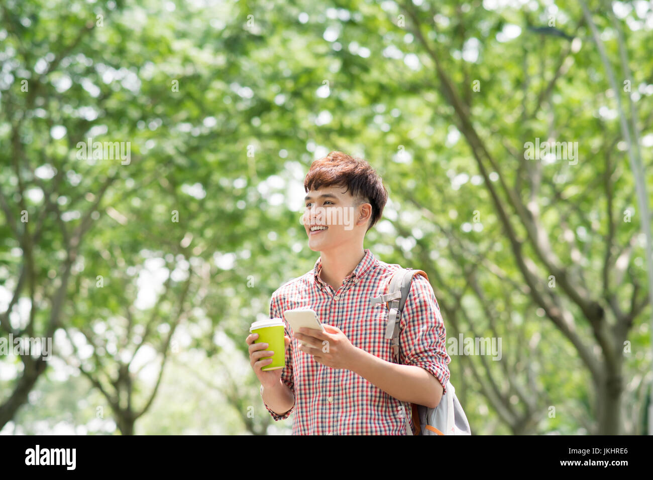 Happy young man texting a message and drinking Stock Photo - Alamy