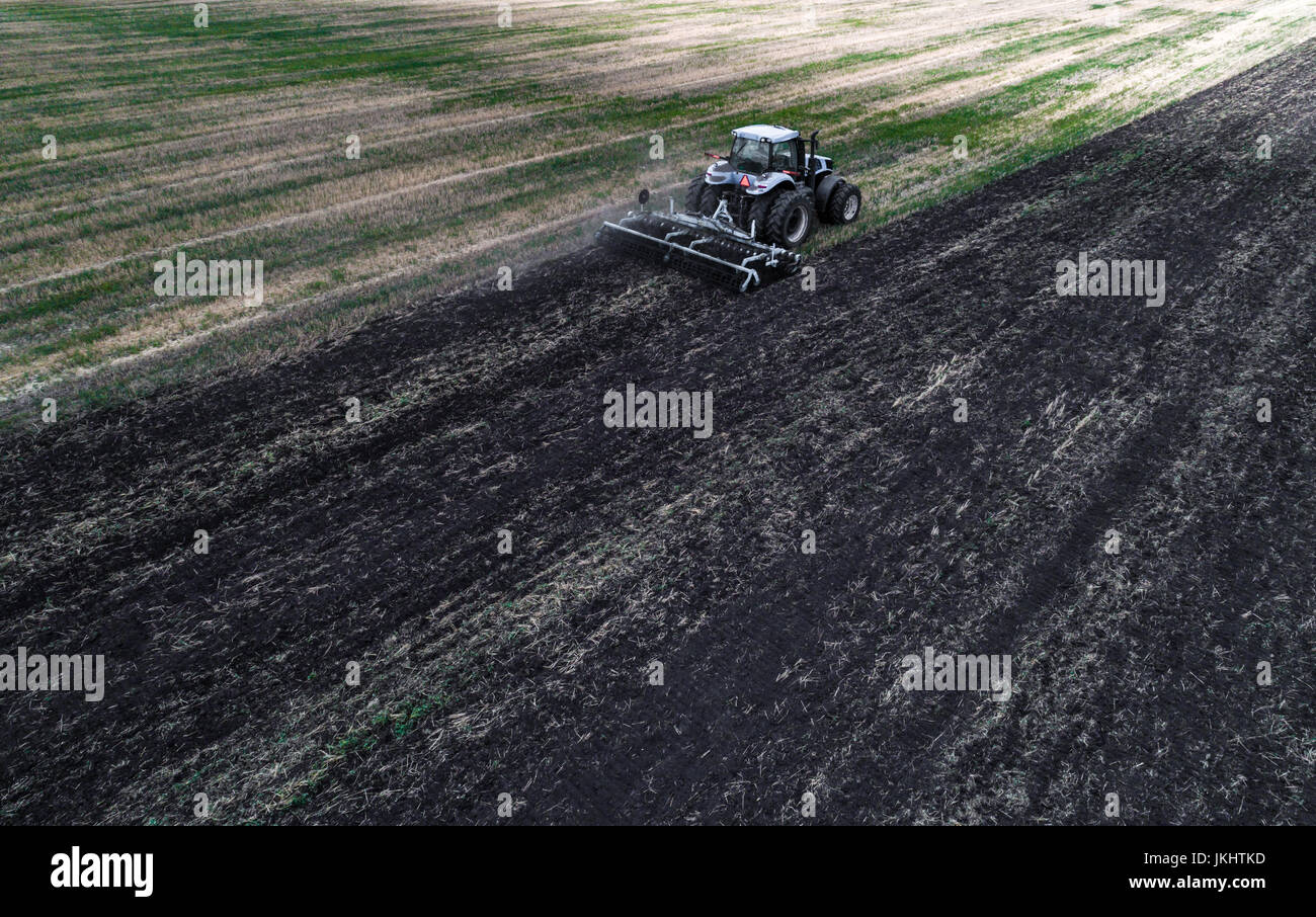The white tractor plows the field against the backdrop of the black ...