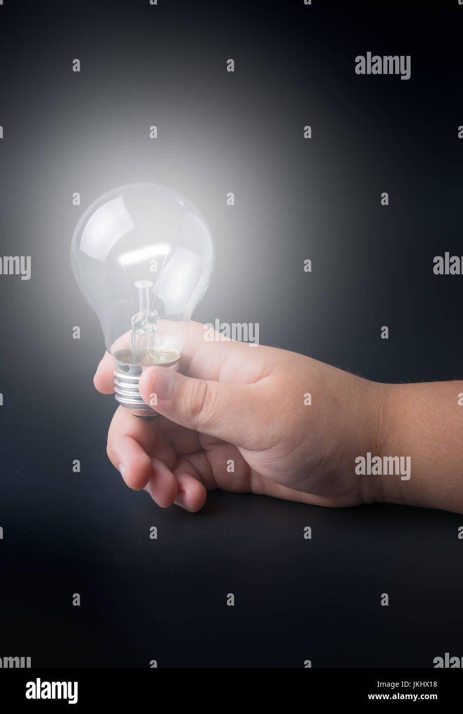 child hand hold bulb light on black background Stock Photo - Alamy