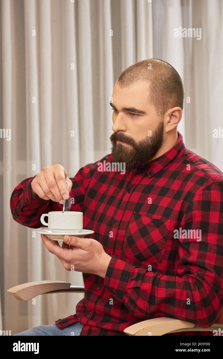 Bearded man mixing coffee Stock Photo - Alamy