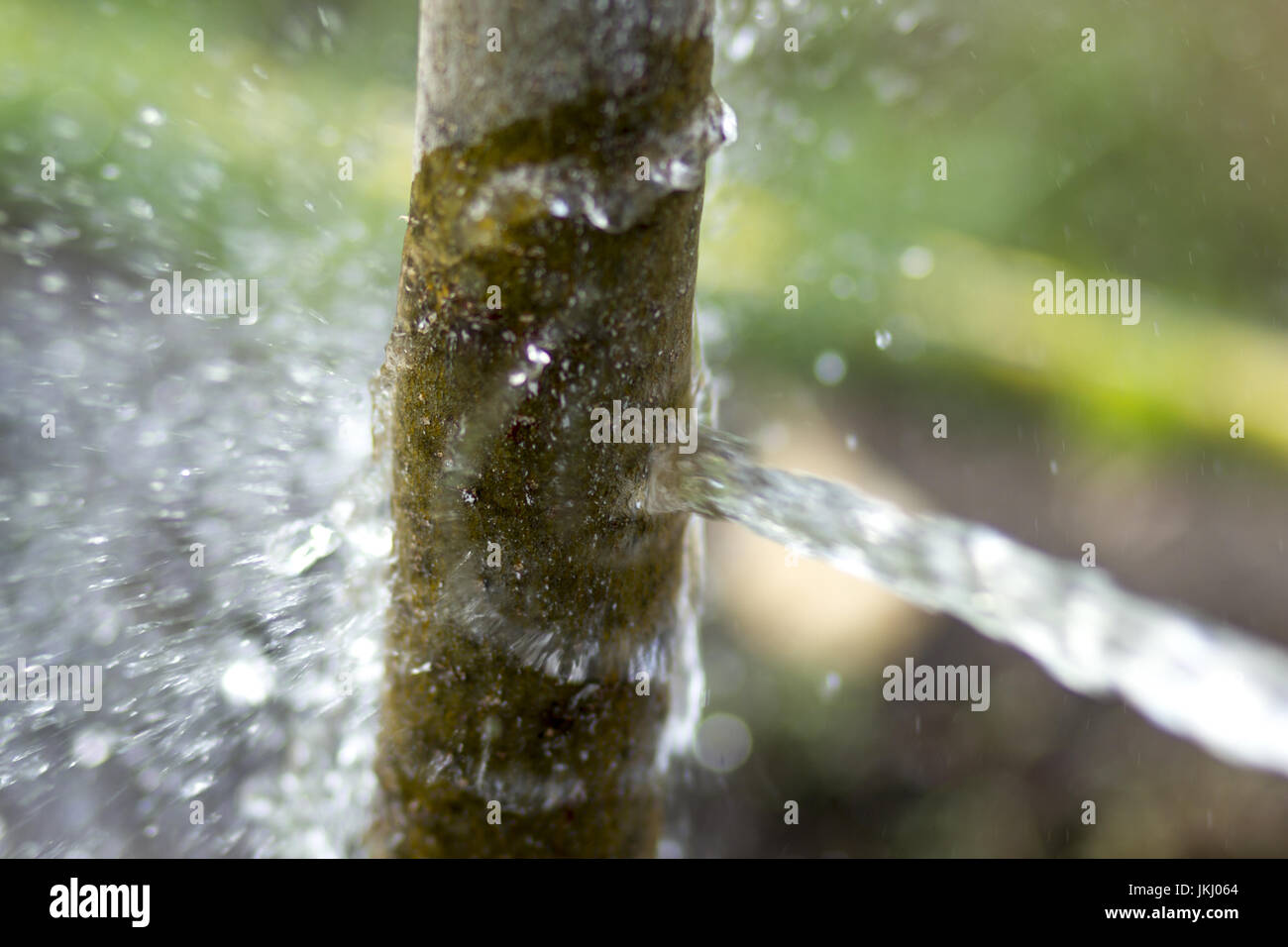 A trickle of water on a blurred background Stock Photo - Alamy