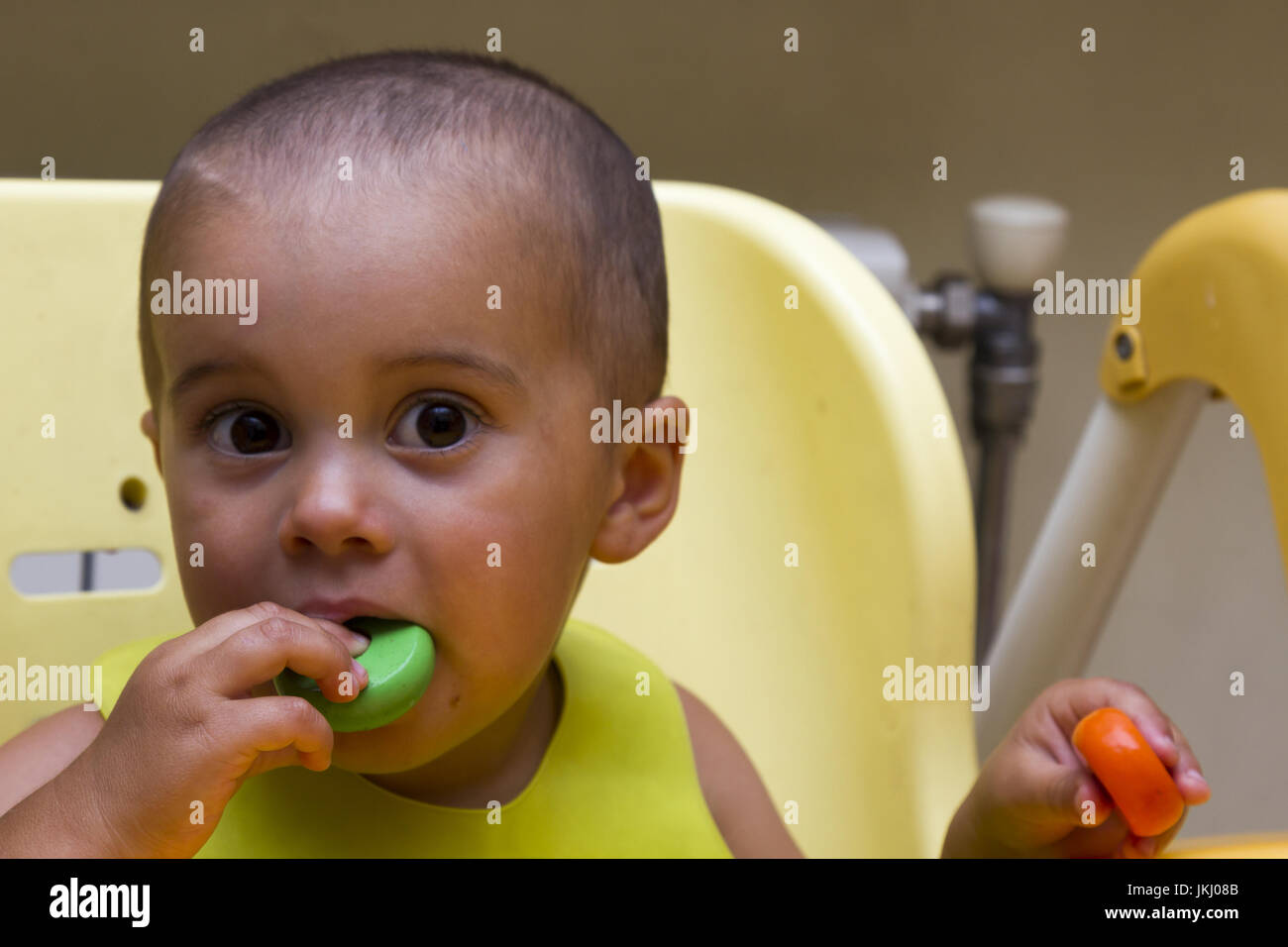Baby boy bites toys Stock Photo - Alamy