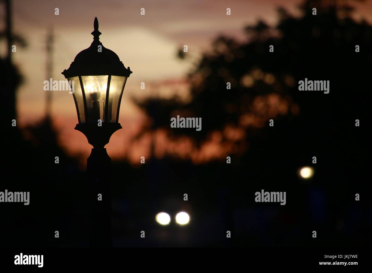 Street Light in Front of Car Approaching with Headlights Illuminated at ...