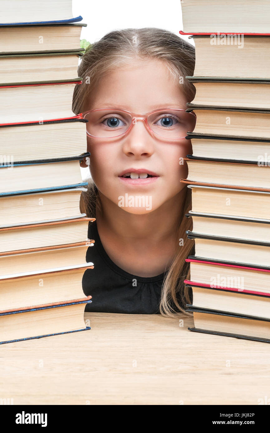 Beautiful schoolgirl with glasses stuck her head between two piles of ...