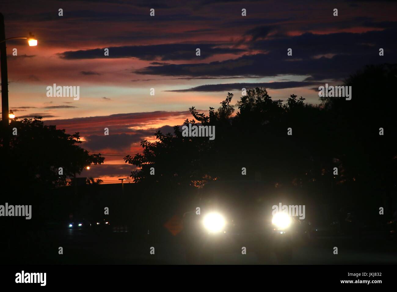 Car Approaching on Neighborhood Street After Sunset under Red Gray and ...