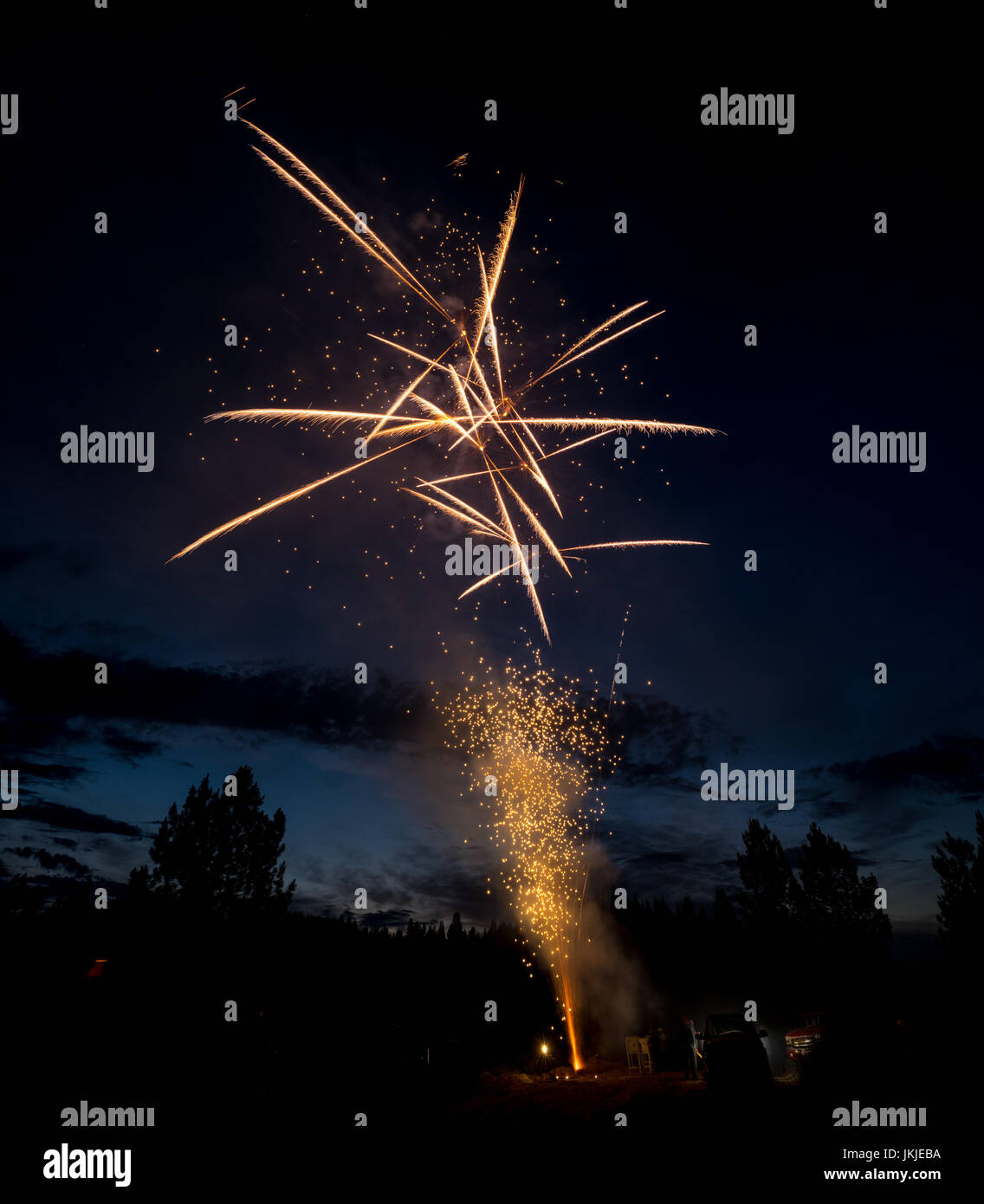 Unique fireworks show with blue sky and pine trees Stock Photo - Alamy