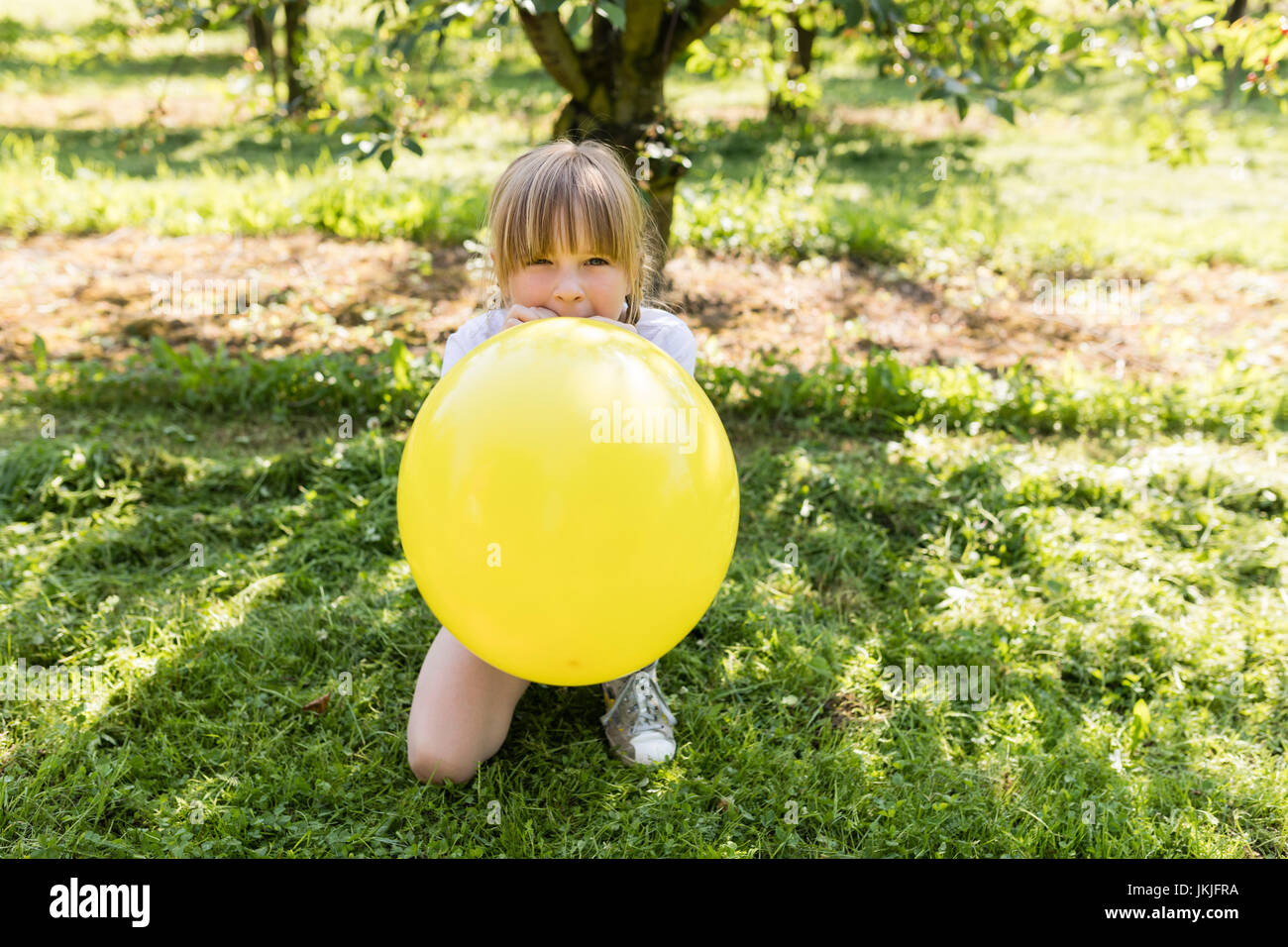 Girl inflating balloon on meadow Stock Photo - Alamy