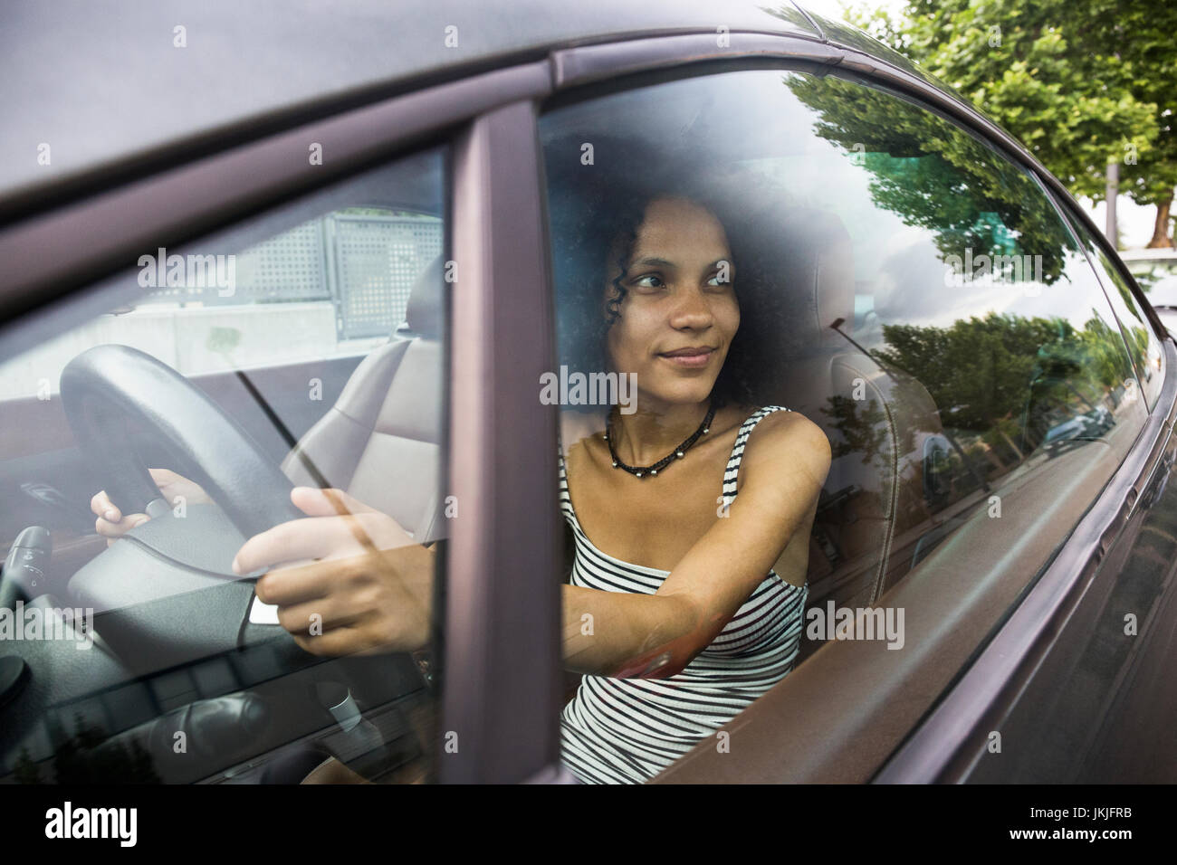 Woman driving a car looking out a car window Stock Photo - Alamy