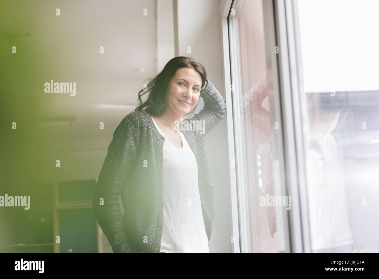 Portrait of smiling woman standing besides window in a loft Stock Photo ...