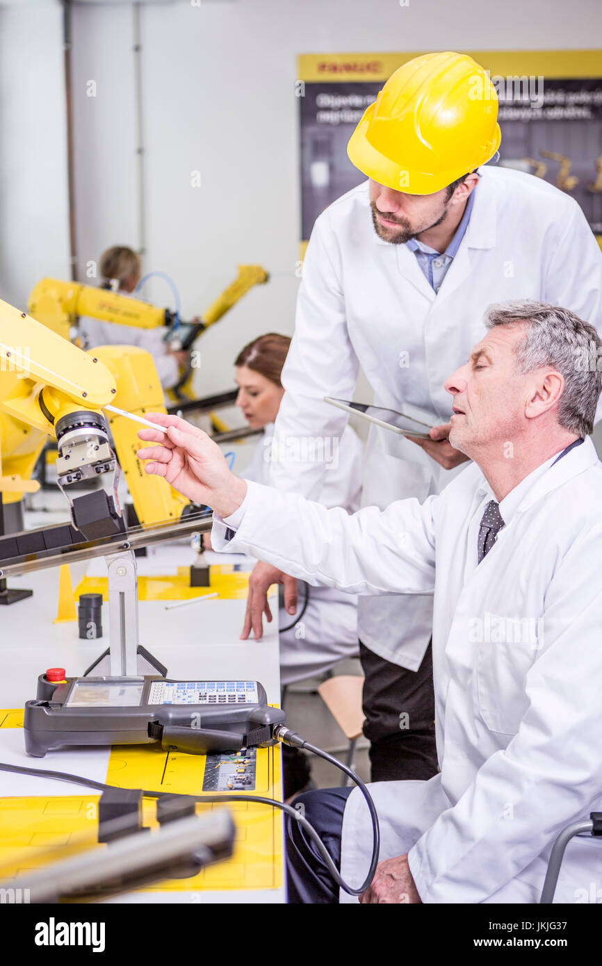 Two engineers examining industrial robot Stock Photo - Alamy