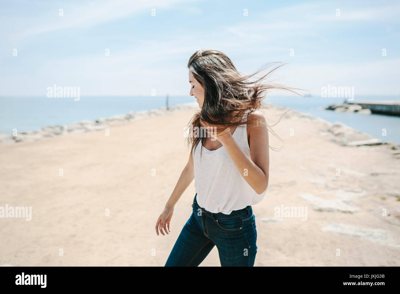 Young woman standing on the beach, enjoying wind Stock Photo - Alamy
