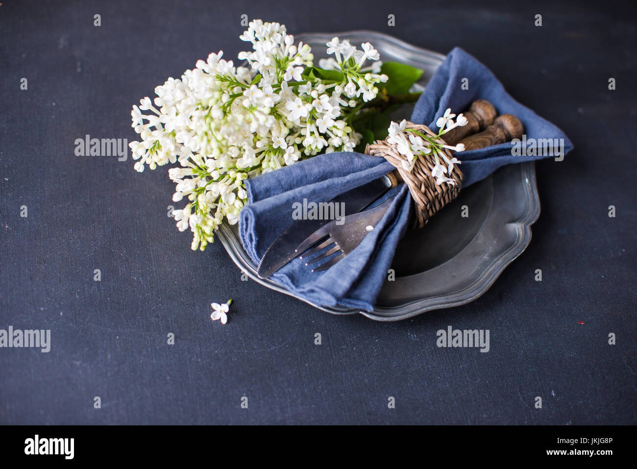 Pring Table Setting With White Lilac Flowers On The Plate With Flatware On Rustic Wooden Table