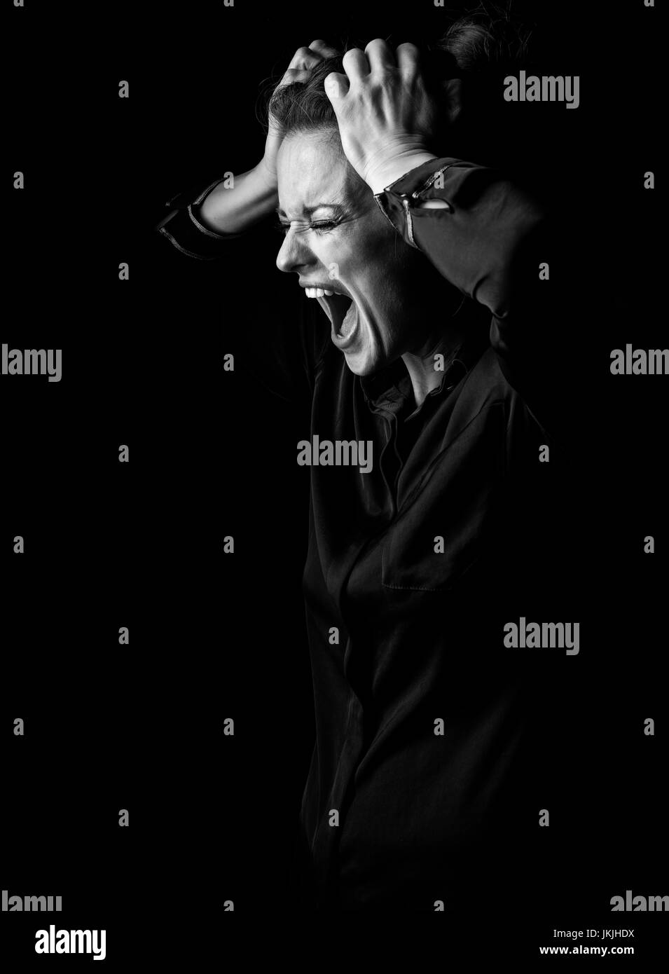 Сoming out into the light. Portrait of angry woman in the dark dress ...