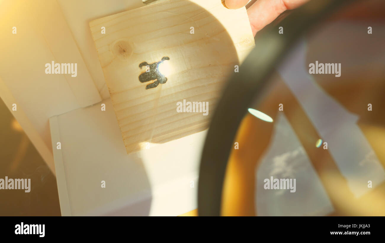 Sunlight focused by a converging magnifying glass can burn wooden bar ...