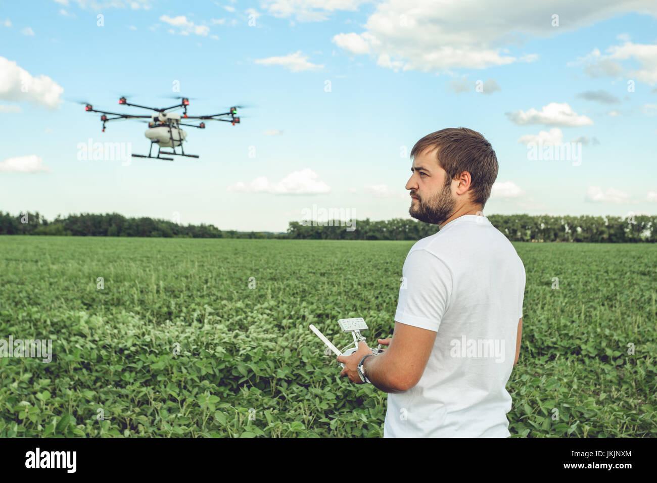 Young man operating of flying drone octocopter at the green field Stock ...