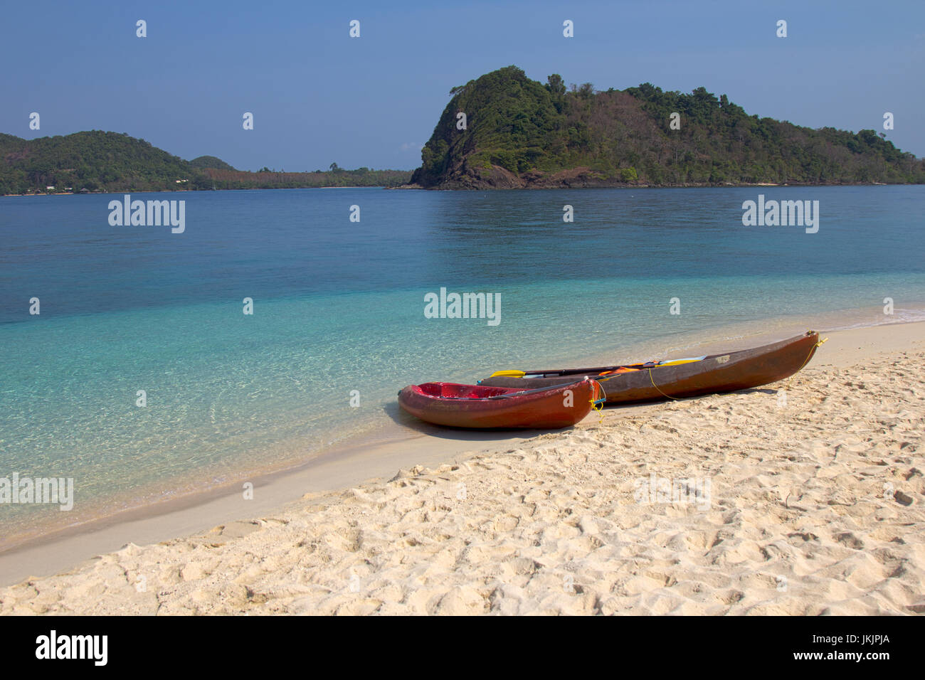 Kayaks on the beach with beautiful crystal clear blue sea and island in ...