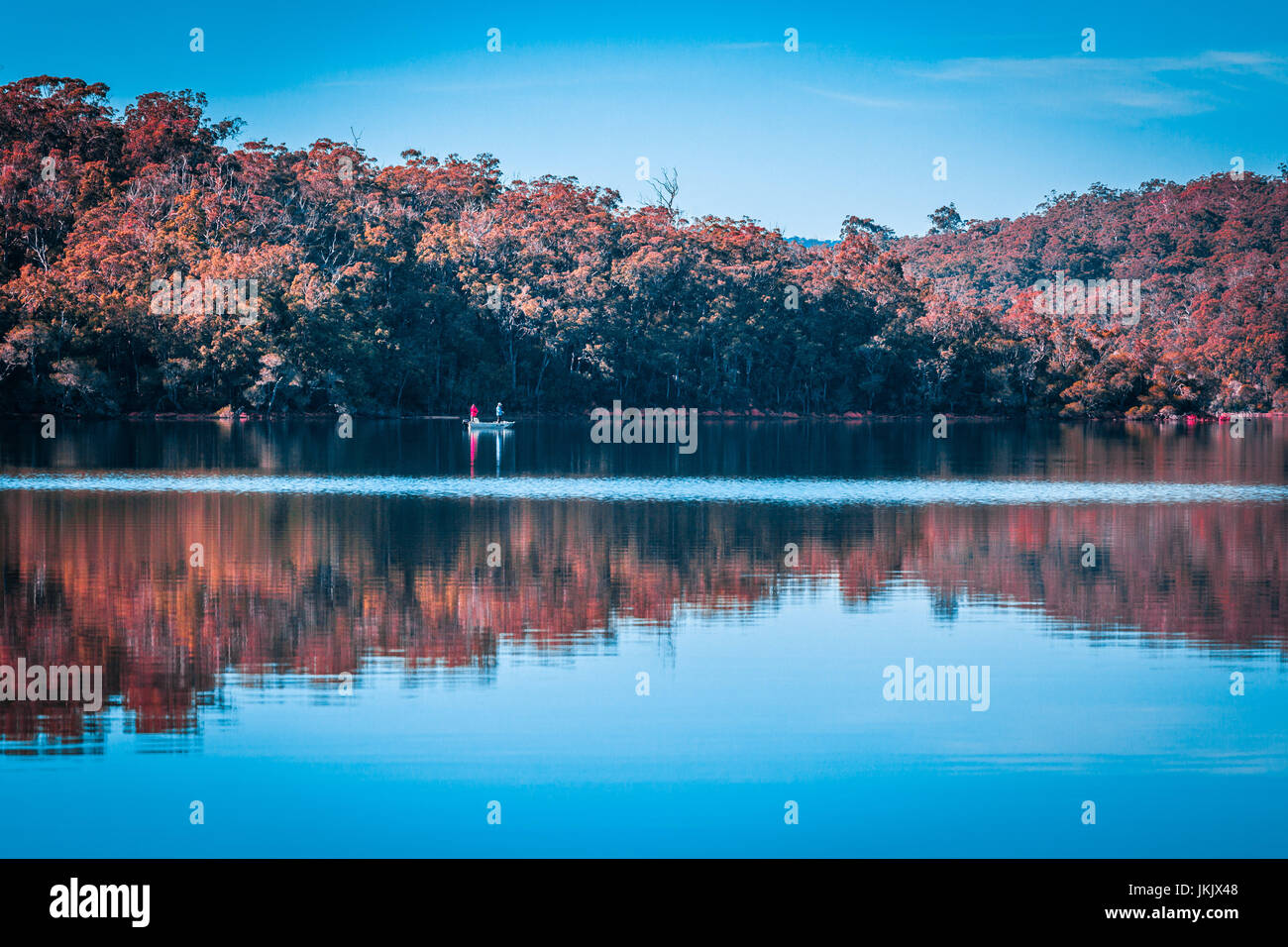 Small boat with two fishermen on smooth river water surface. Native ...