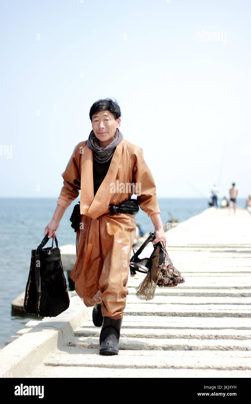 A scuba diver/fisherman in retro gear emerging from the ocean on Wonsan ...