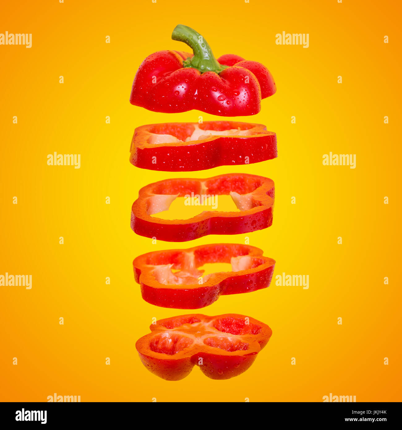 Flying red capsicum. Sliced floating bell pepper on an orange ...