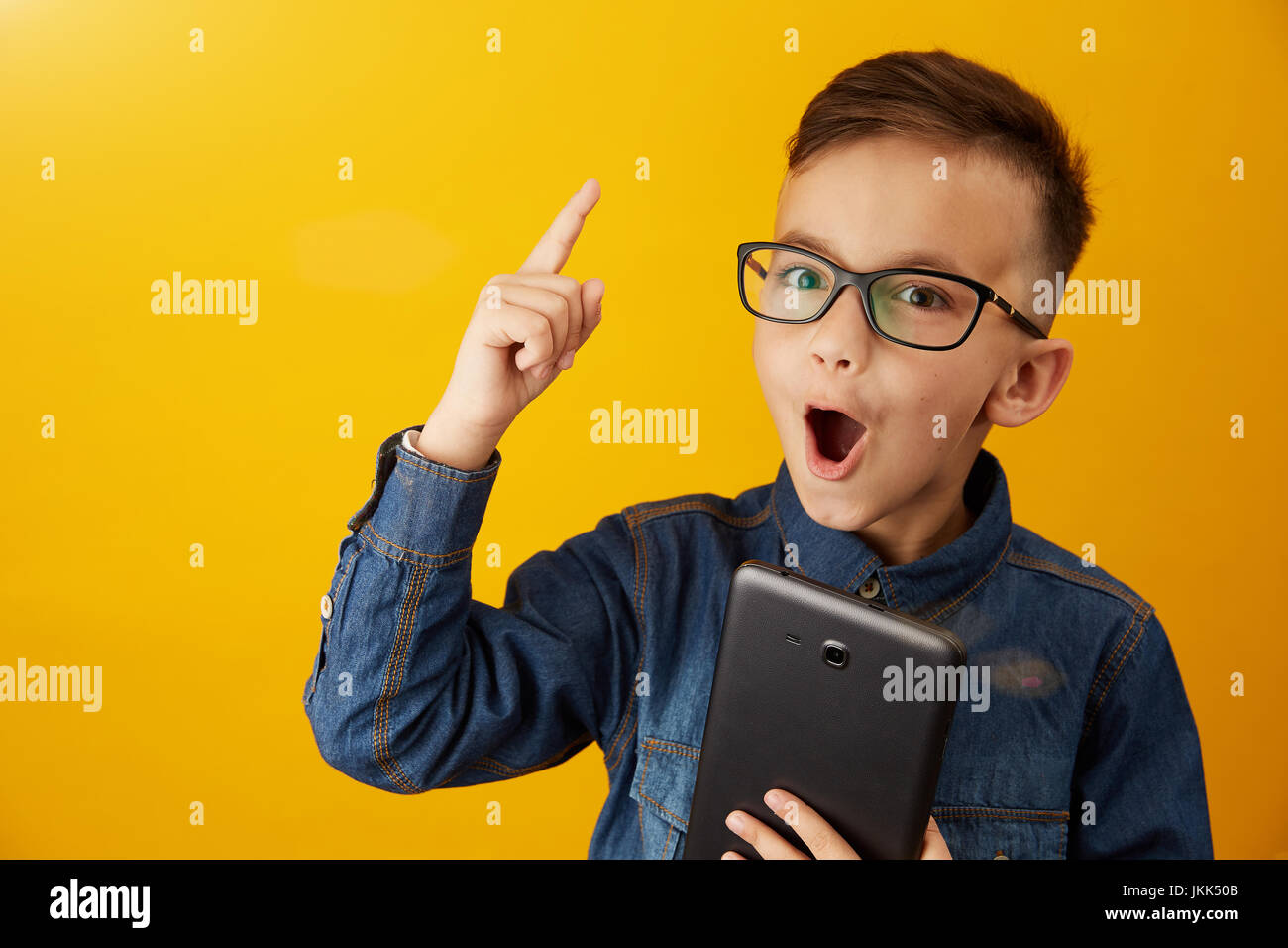 Happy smiling little boy holding tablet, over yellow background Stock ...