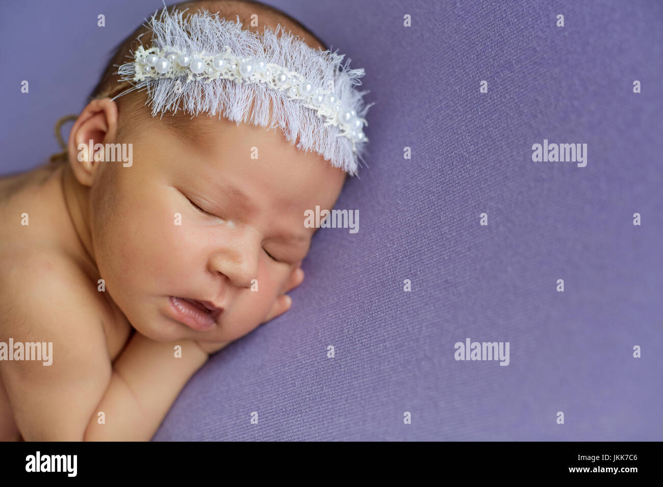 Newborn 4 day old baby boy lying on his back relaxing under a blue wrap ...