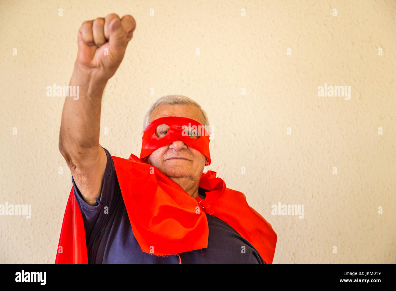 view from bottom of old man dressed as superhero sticking chest out ...