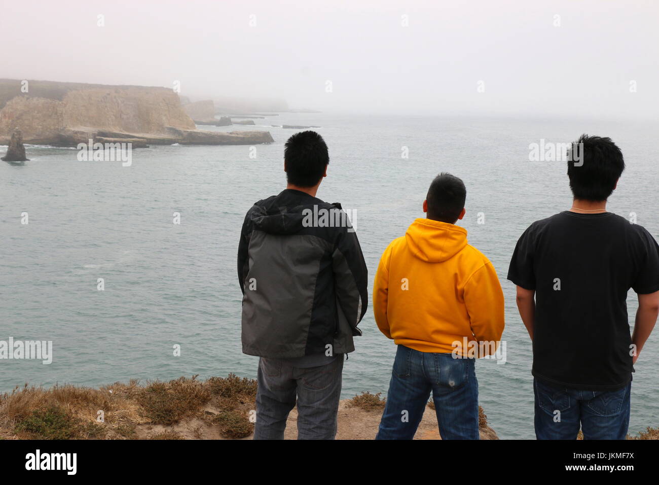 Three young Asian men on a hike overlooking the California coast ...
