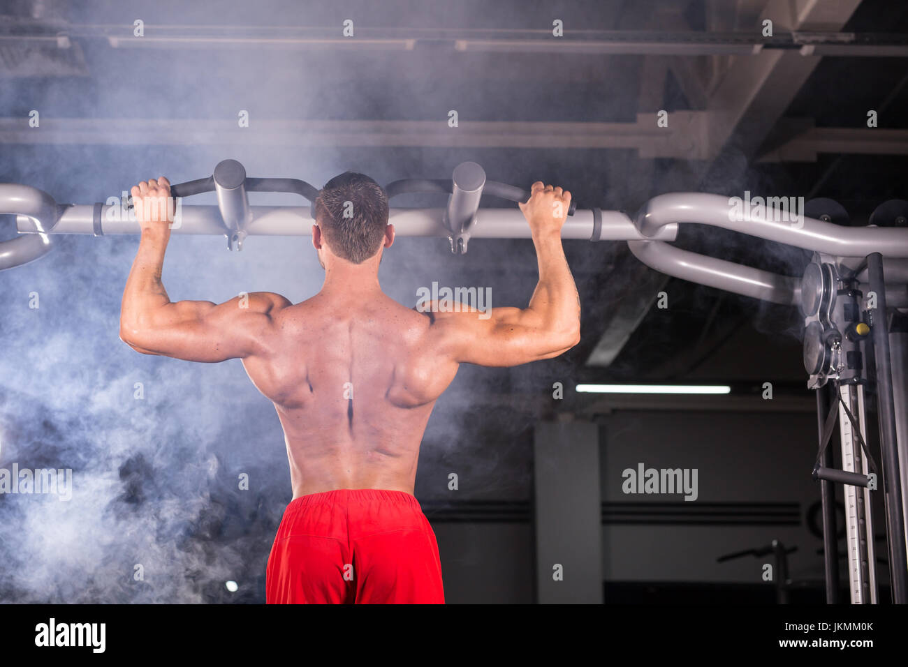 Strong man doing pull-ups on a bar in a gym Stock Photo - Alamy