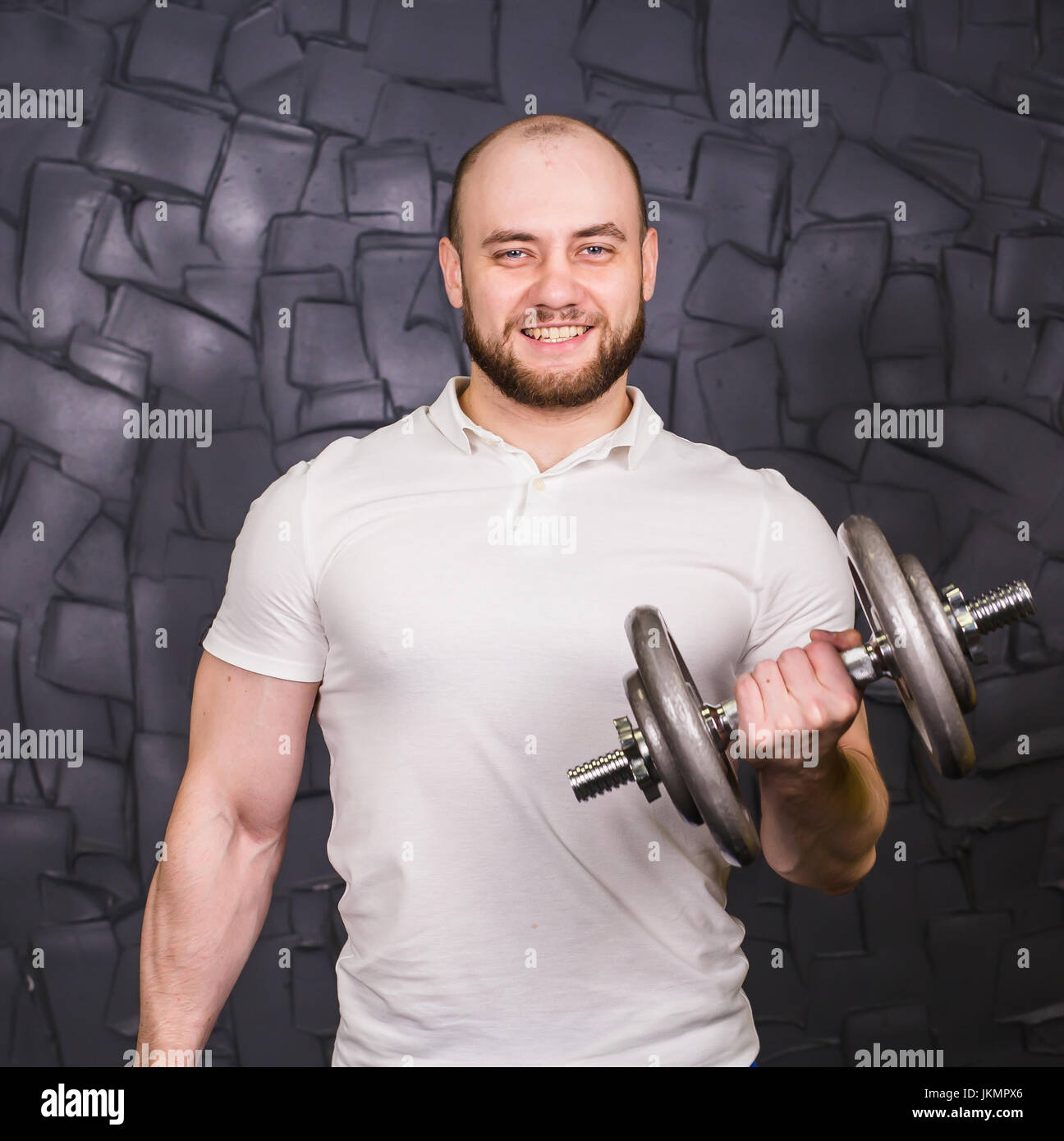 Good looking young man lifting dumbbells and working on his biceps ...