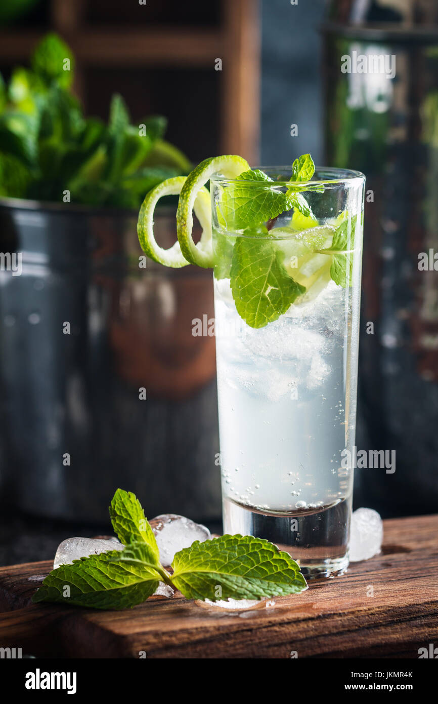 cocktail with lime and mint in short glass on dark stone background ...