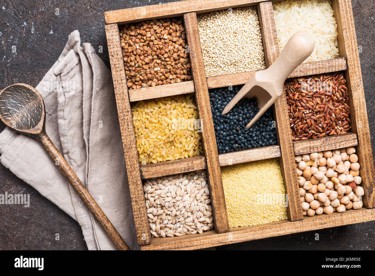 assortment of different cereals and seeds in a box on dark brown ...