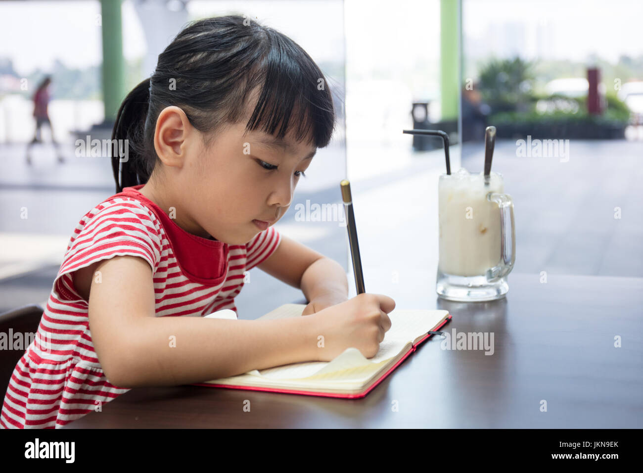 Asian Chinese little girl doing homework at outdoor cafe Stock Photo ...