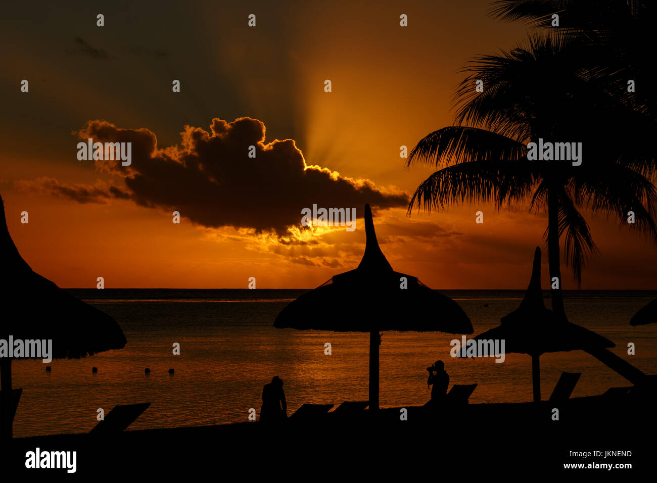 Sunset on the beach with silhouettes of a photographer and his model ...